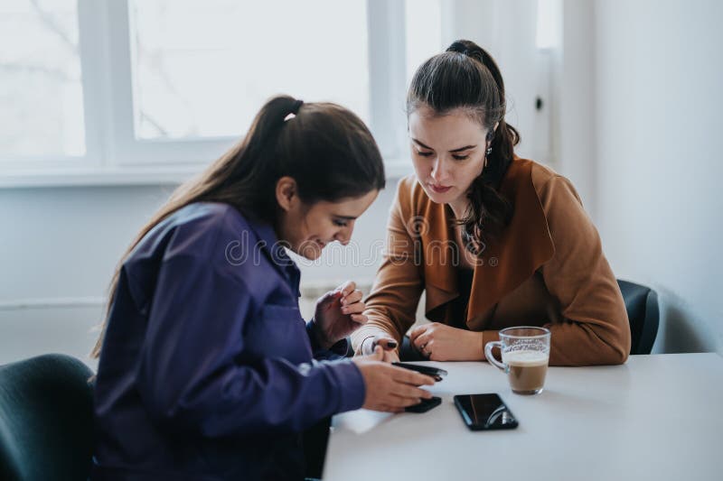 Two Young Women Collaborating with Technology Over Coffee in a Modern ...