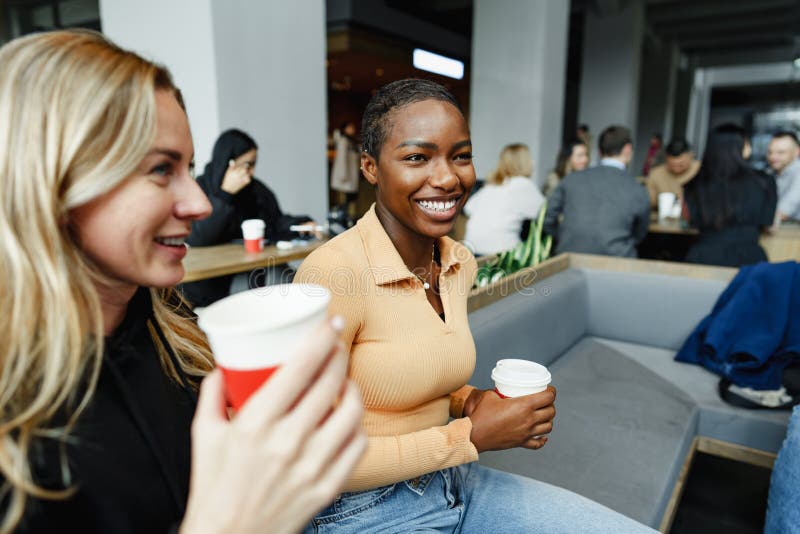 Two Young Women Friends Enjoying Coffee Together In A Coffee Shop Stock
