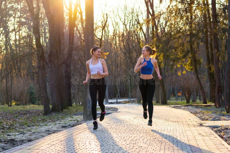 Two Young Women Run Along the Path in the Park at Sunset Stock Photo ...