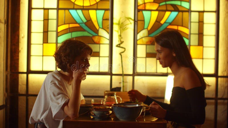 Two Girls Sit at a Table in a Cafe and Talk Stock Photo - Image of ...