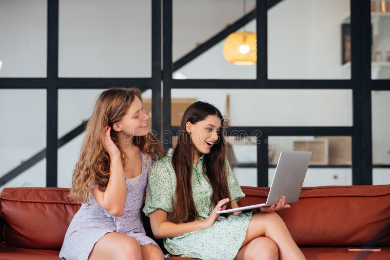 Two Young Women Using Computer while Sitting on Couch. Stock Photo ... Two Young Women Using Computer while Sitting on Couch. Stock Photo ...