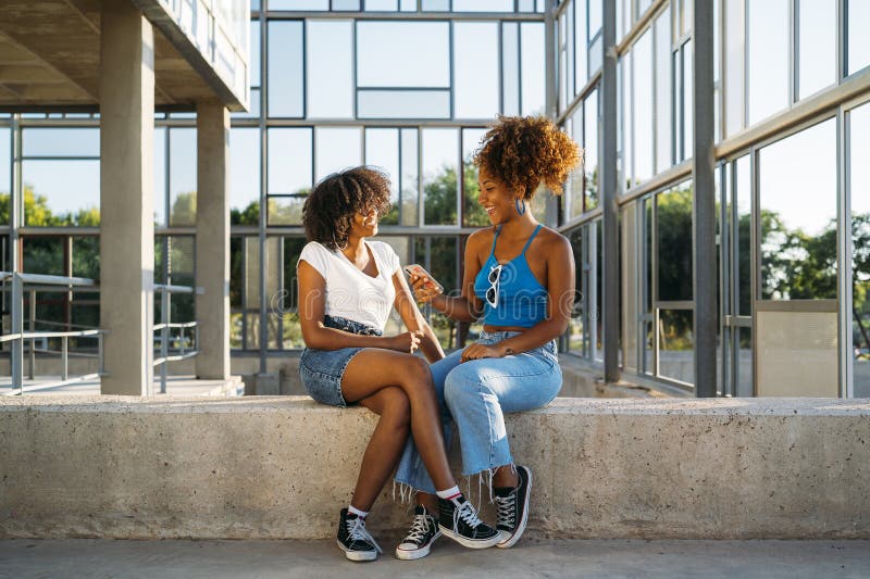 Two Young Women Using Smartphone Outside Modern Building Stock Photo ...