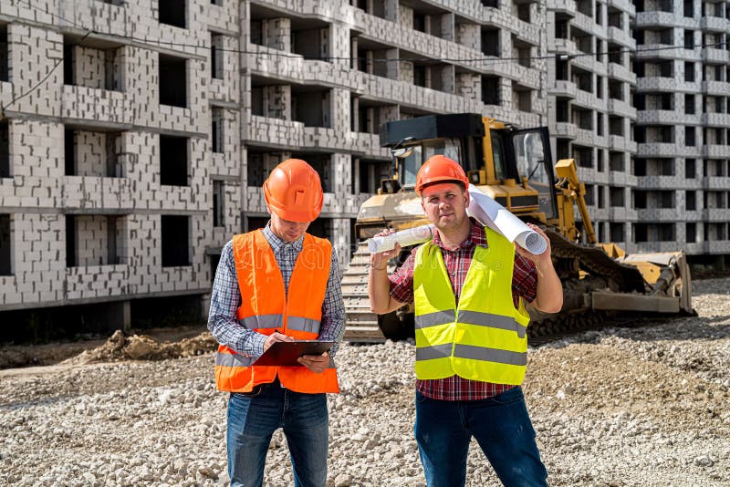 Two Young Workers in Uniforms Discuss the Process of Building a House ...