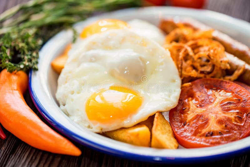 Typial Breakfast with Eggs, Tomato, Onion Rings and Sausage on Plate ...