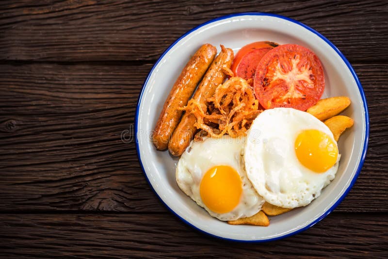 Typial Breakfast with Eggs, Tomato, Onion Rings and Sausage on Plate ...