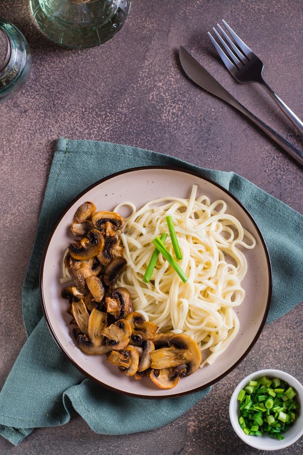 Udon Noodles, Fried Champignons and Greens on a Plate on the Table Top ...