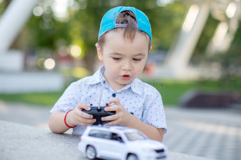 Um Menino Brinca Com Um Carro De Brinquedo No Rádio Segurando Um