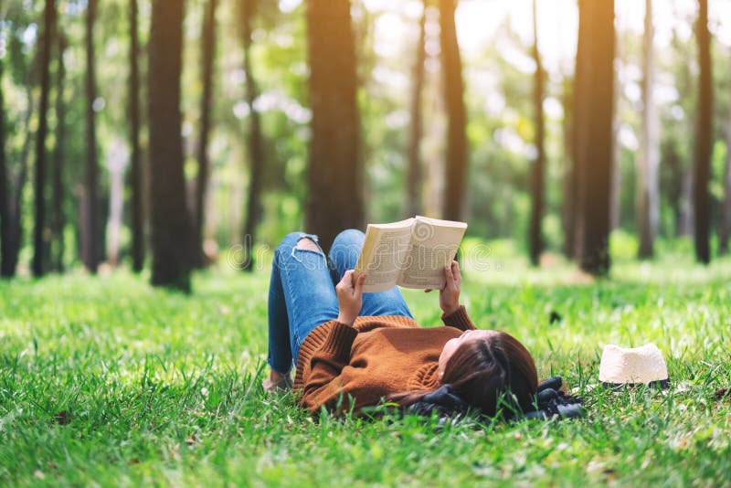 Uma Mulher Deitada E Lendo Um Livro No Parque Foto De Stock Imagem De