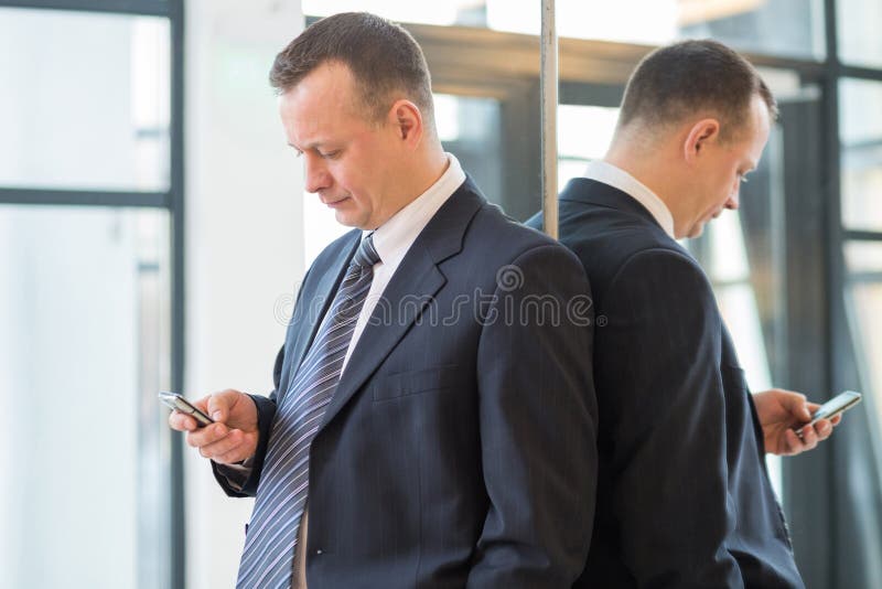 Un Hombre De Negocios Se Coloca Con El Suyo De Nuevo Al Espejo Imagen ... Un Hombre De Negocios Se Coloca Con El Suyo De Nuevo Al Espejo Imagen ...