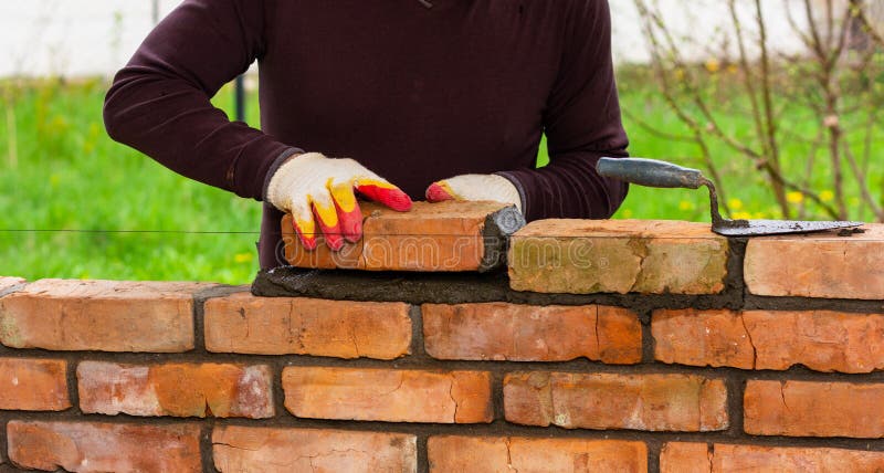 Un Homme Construit Un Mur De Briques Pose Une Brique Sur Un Ciment Et ... Un Homme Construit Un Mur De Briques Pose Une Brique Sur Un Ciment Et ...
