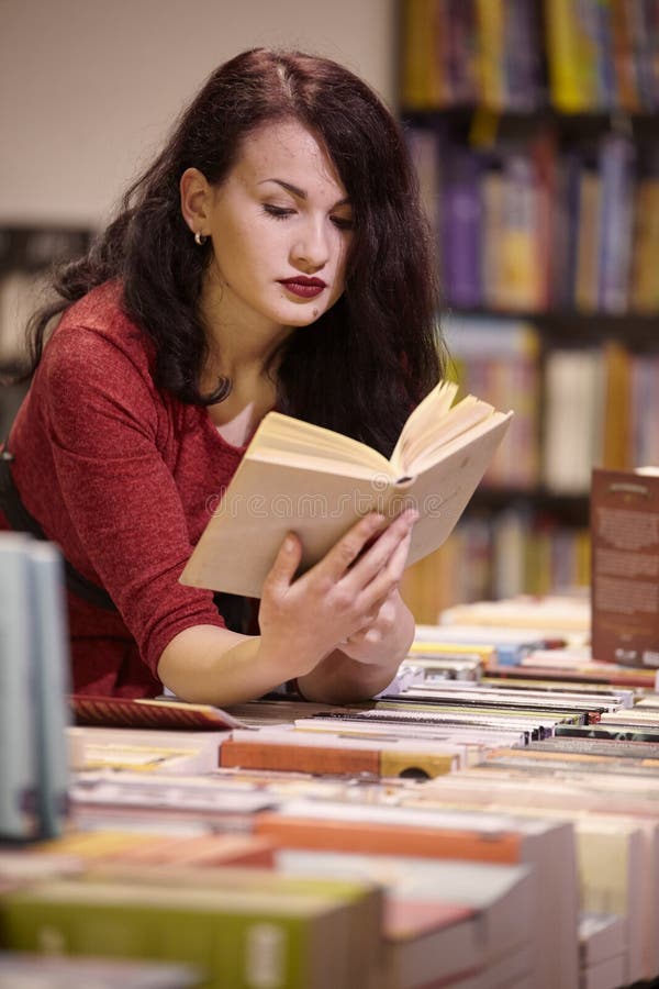 Una Mujer Joven, Rodeada Con Los Libros, Leyendo Imagen de archivo ...
