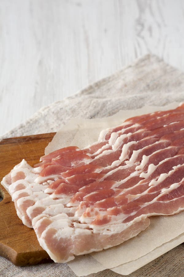 Uncooked Raw Bacon on a Rustic Wooden Board on a White Wooden Surface ...