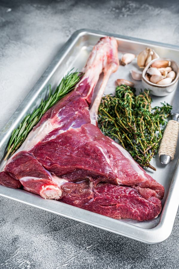 Uncooked Raw Goat Leg with Herbs on Butcher Cutting Board. Black Wooden ...