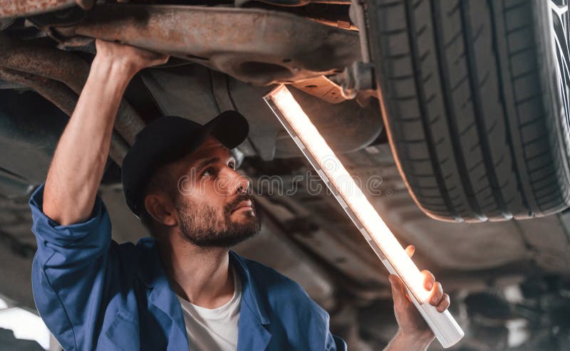 Under Car, Using Lighting Device. Auto Mechanic Working in Garage Stock ...