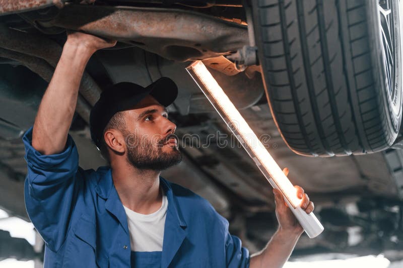 Under Car, Using Lighting Device. Auto Mechanic Working in Garage Stock ...