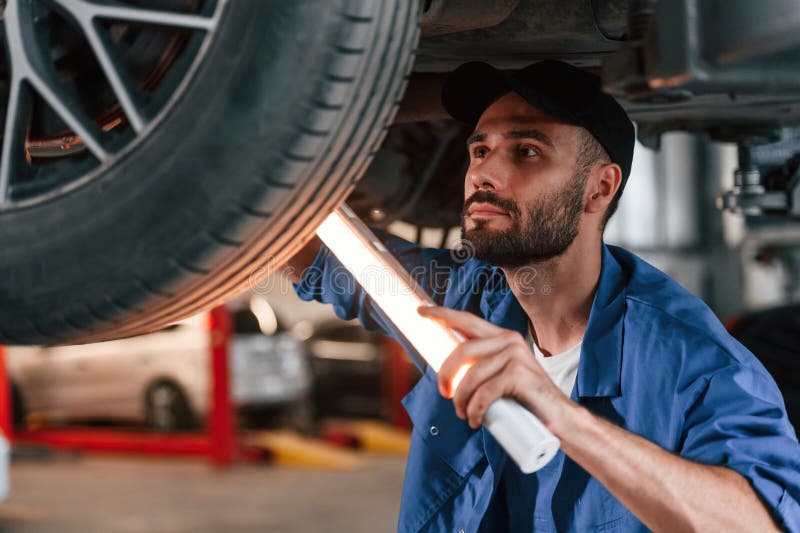 Under Car, Using Lighting Device. Auto Mechanic Working in Garage Stock ...