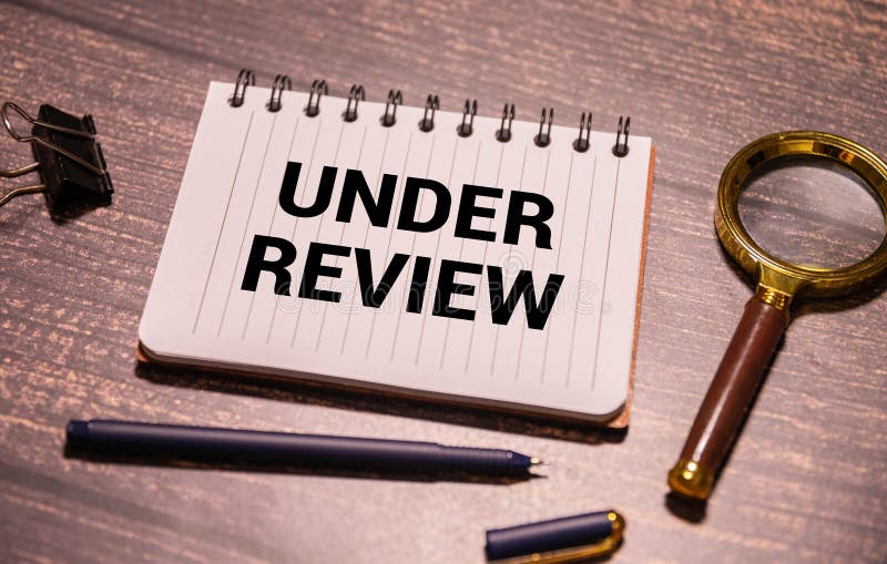 Under Review. Text is Written on White Paper on a Wooden Table Stock ...