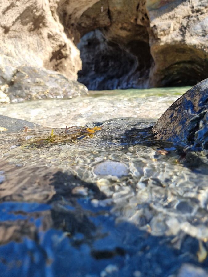 Under the rocks stock image. Image of cave, water, ocean - 220691733