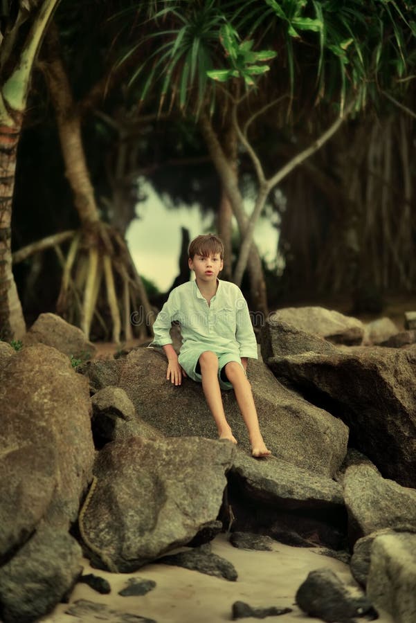 Under a Tree on a Large Rock Sits a Boy Stock Image - Image of ...