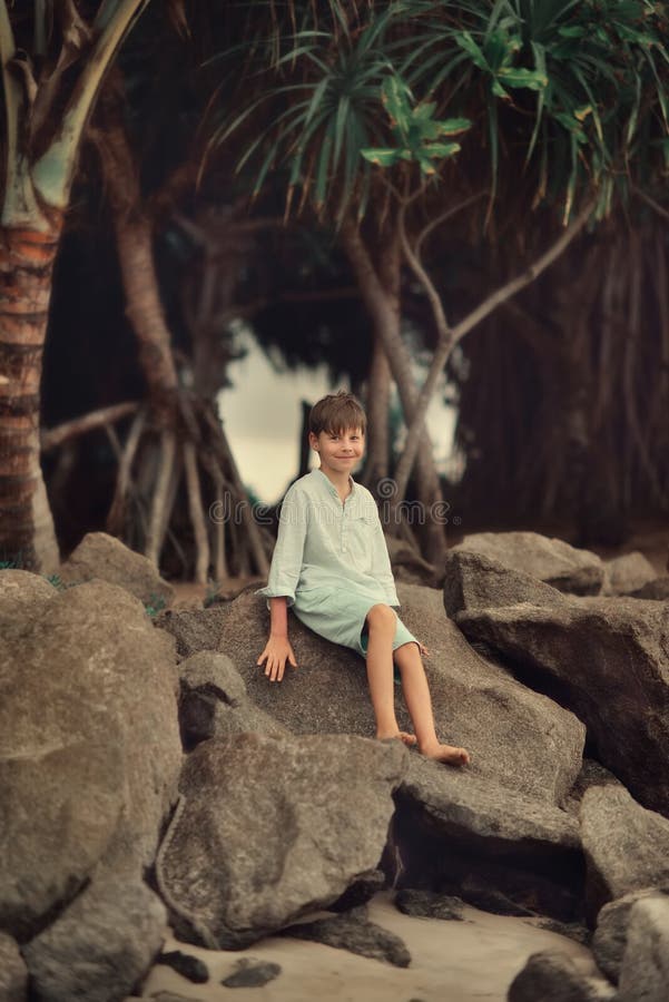 Under a Tree on a Large Rock Sits a Boy Stock Photo - Image of ...