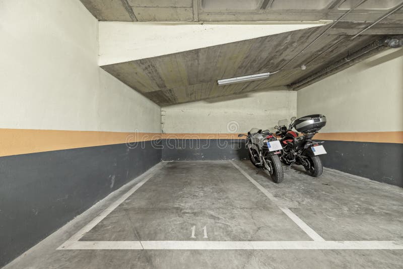 An Underground Garage with Empty Spaces and Some Parked Motorcycles ...