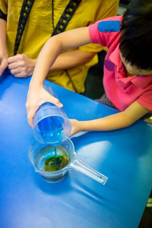 Une Fille Versant La Solution Chimique Bleue Dans La Solution Acide Et ...