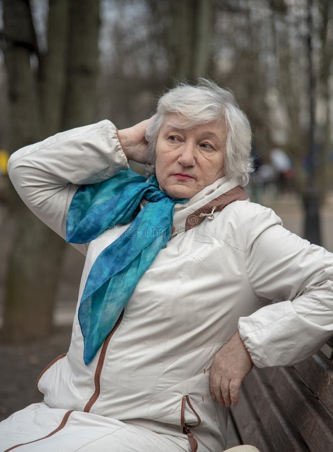 Une élégante Vieille Femme Aux Cheveux Gris Est Assise Sur Un Banc Du
