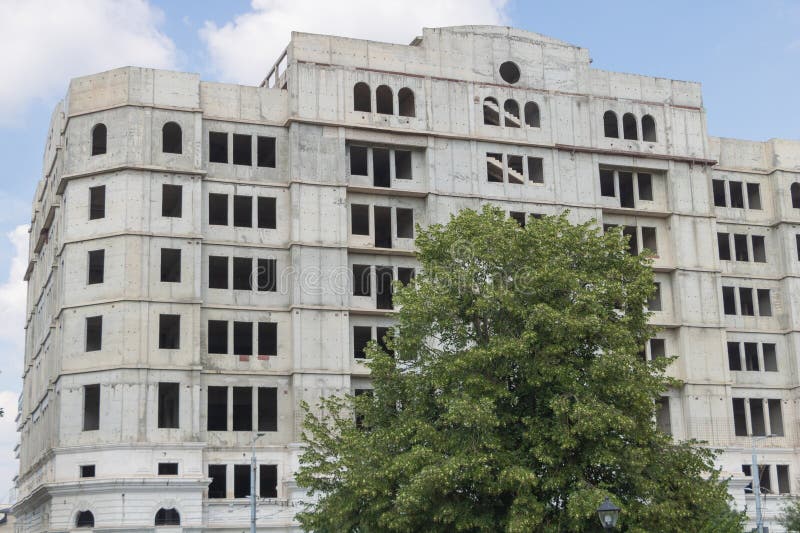 An Unfinished Building with a Silver Stone Facade, Tall Windows with ...