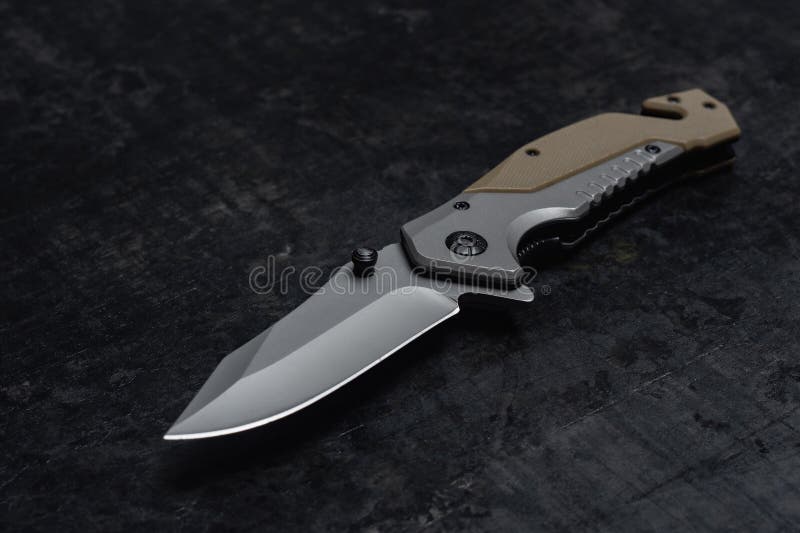 An Unfolded Tactical Military Knife with a Sharp Blade. Tool on Dark ...