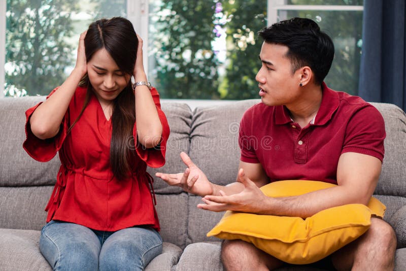 Unhappy Couple Sitting Beside Each Other On The Sofa And Avoid Talking