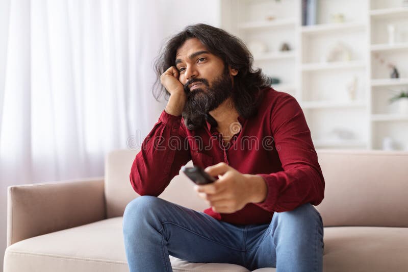 Unhappy Eastern Guy with Remote Control Sitting on Couch Stock Image ...