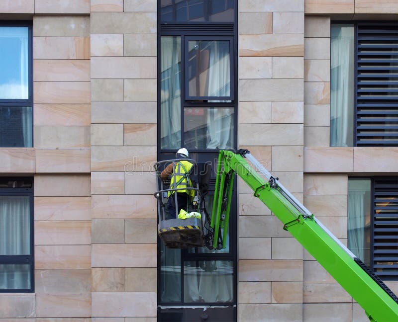 Unidentifiable Construction Worker in a Green Aerial Work Platform on a ...