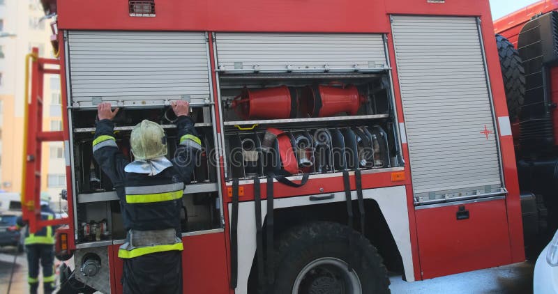 Uniformed Fireman Closes a Roller Shutter on the Side of a Fire Engine ...