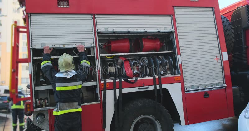 Uniformed Fireman Closes a Roller Shutter on the Side of a Fire Engine ...