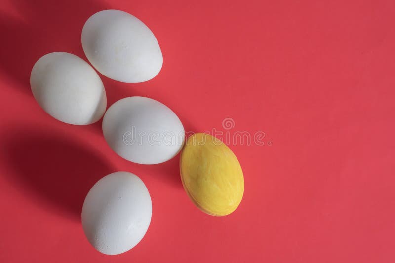 A Unique Yellow Painted Egg among White Eggs on a Bright Red Surface ...