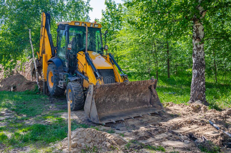 Universal Wheel Backhoe Loader Digging a Trench for the Laying of Pipes ...