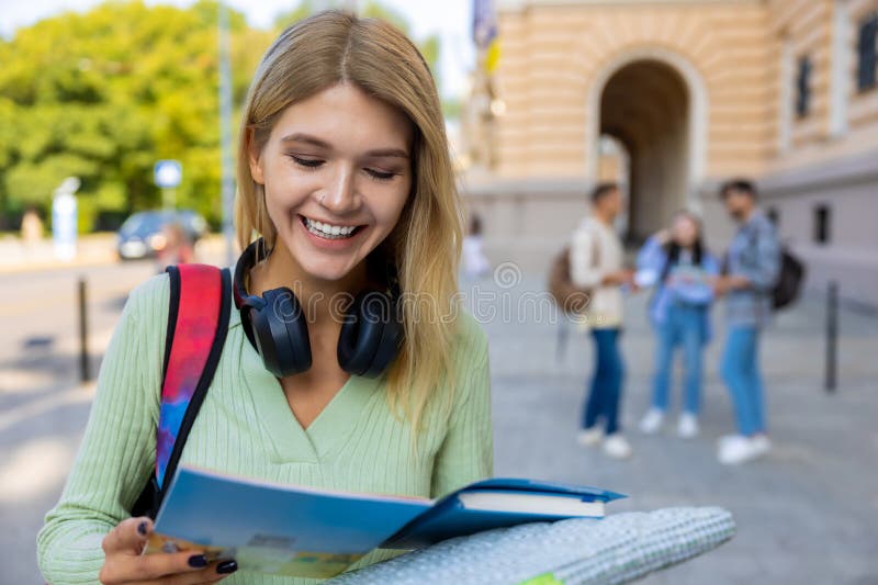 University Female Student Standing with Book in Hands Reading with ...