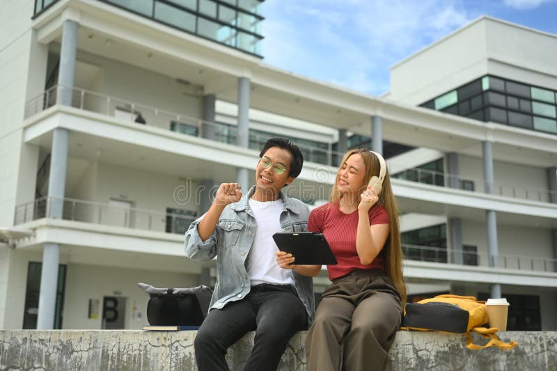 University Student Sitting on a Ledge in Front of Building and Talking ...