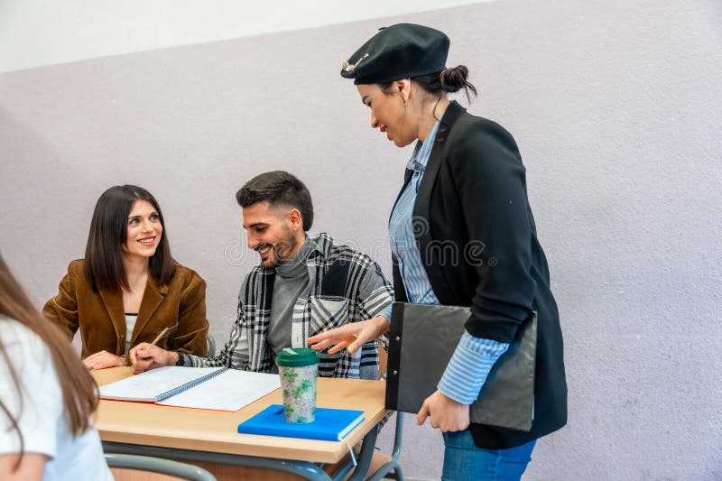Professor Helping University Students Studying Together at Desk in ...