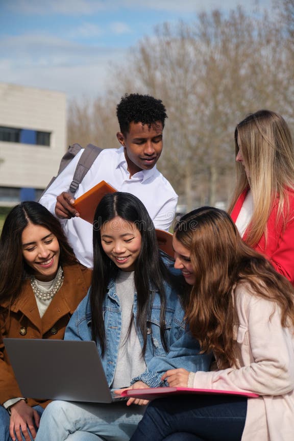 University Students Collaborating on a Project Using Laptop Outdoors ...