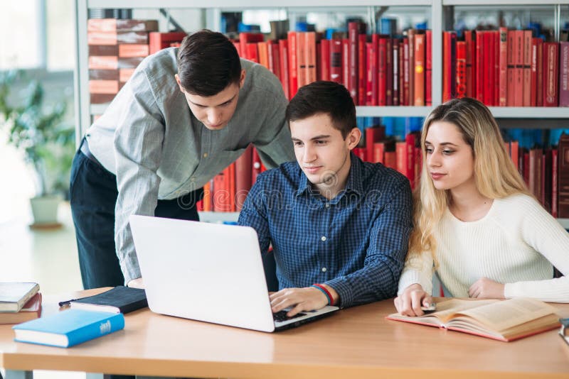 University Students Sitting Together at Table with Books and Laptop ...