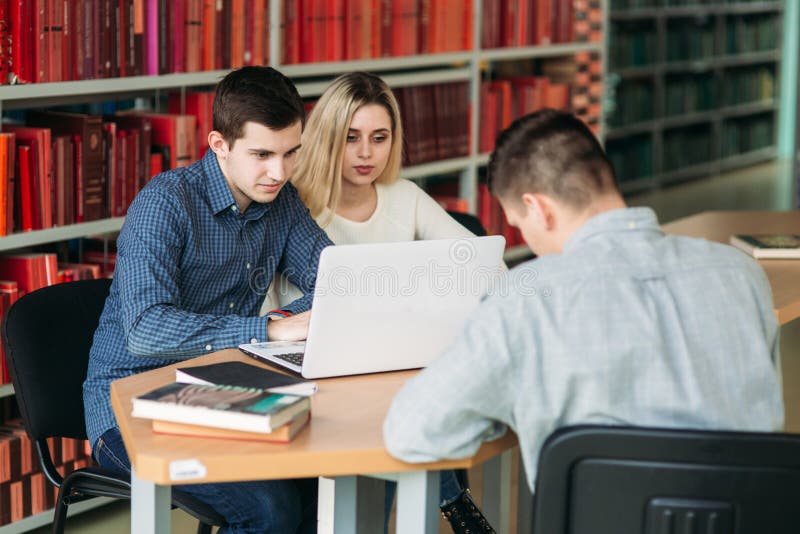 University Students Sitting Together at Table with Books and Laptop ...