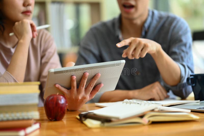 University Students Using Digital Tablet, Collaborating on a Project in ...