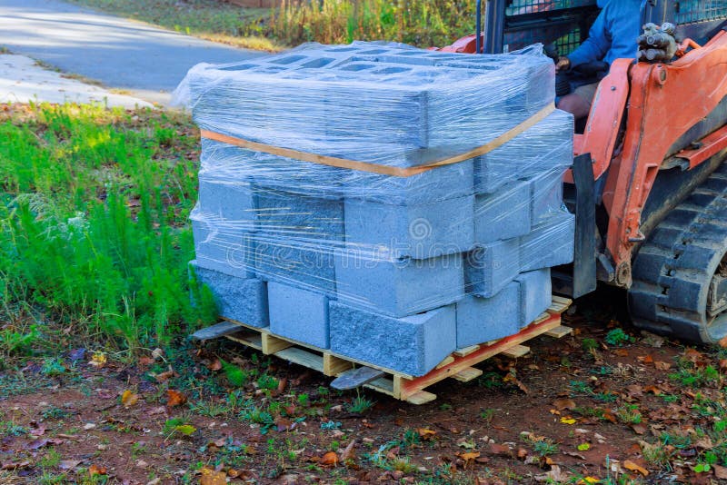 Unloading Pallets Of Concrete Blocks For Retaining Walls With A Small Tractor Stock Image