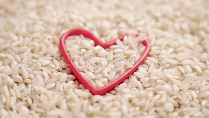 Unprocessed Integral Brown Rice Seeds Falling on a Full Red Heart Shape ...