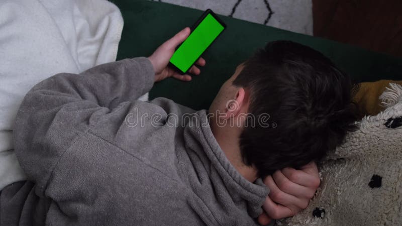 Unrecognised Man on a Sofa in a Robe is Watching a Phone with a Green ...