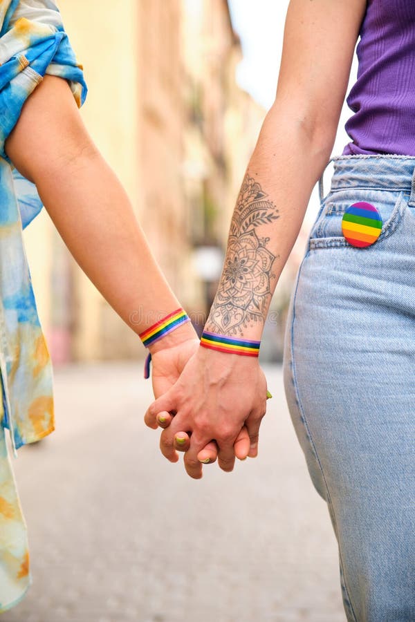 Unrecognizable Lesbian Couple Holding Hands With Lgbtq Flag Bracelets