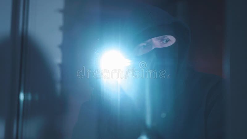 An Unrecognizable Robber in a Mask and with a Flashlight Wants To Break ...
