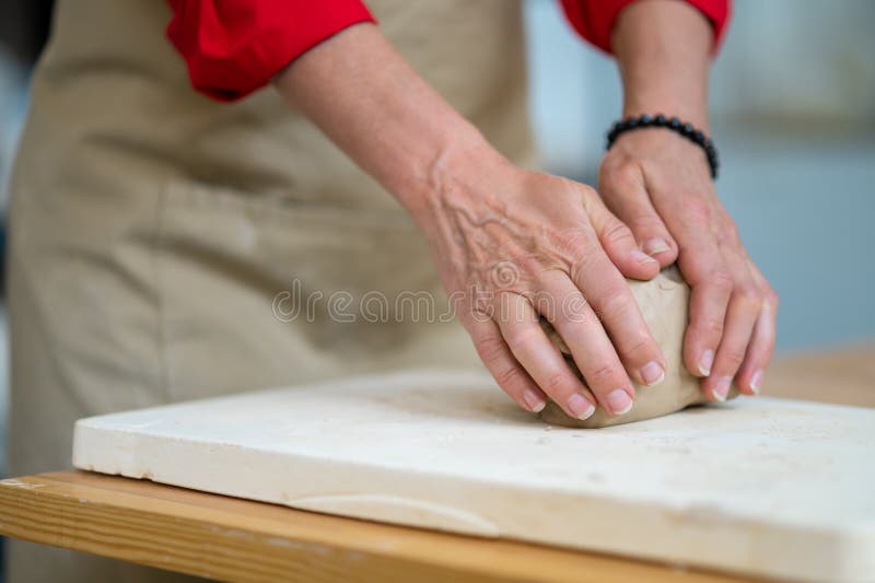 Unrecognizable Woman Wedging Clay with Hands Standing Behind Table in ...
