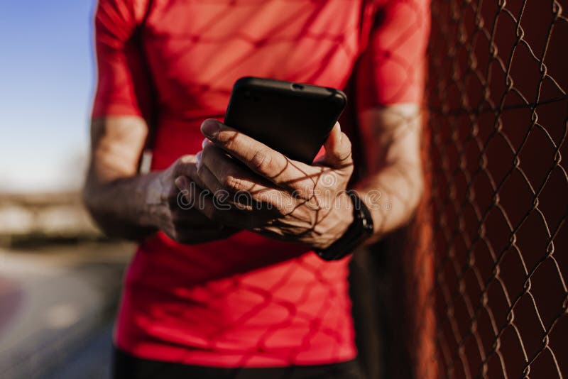 Unrecognizable Young Runner Man Using Mobile Phone at Sunset. Sports ...